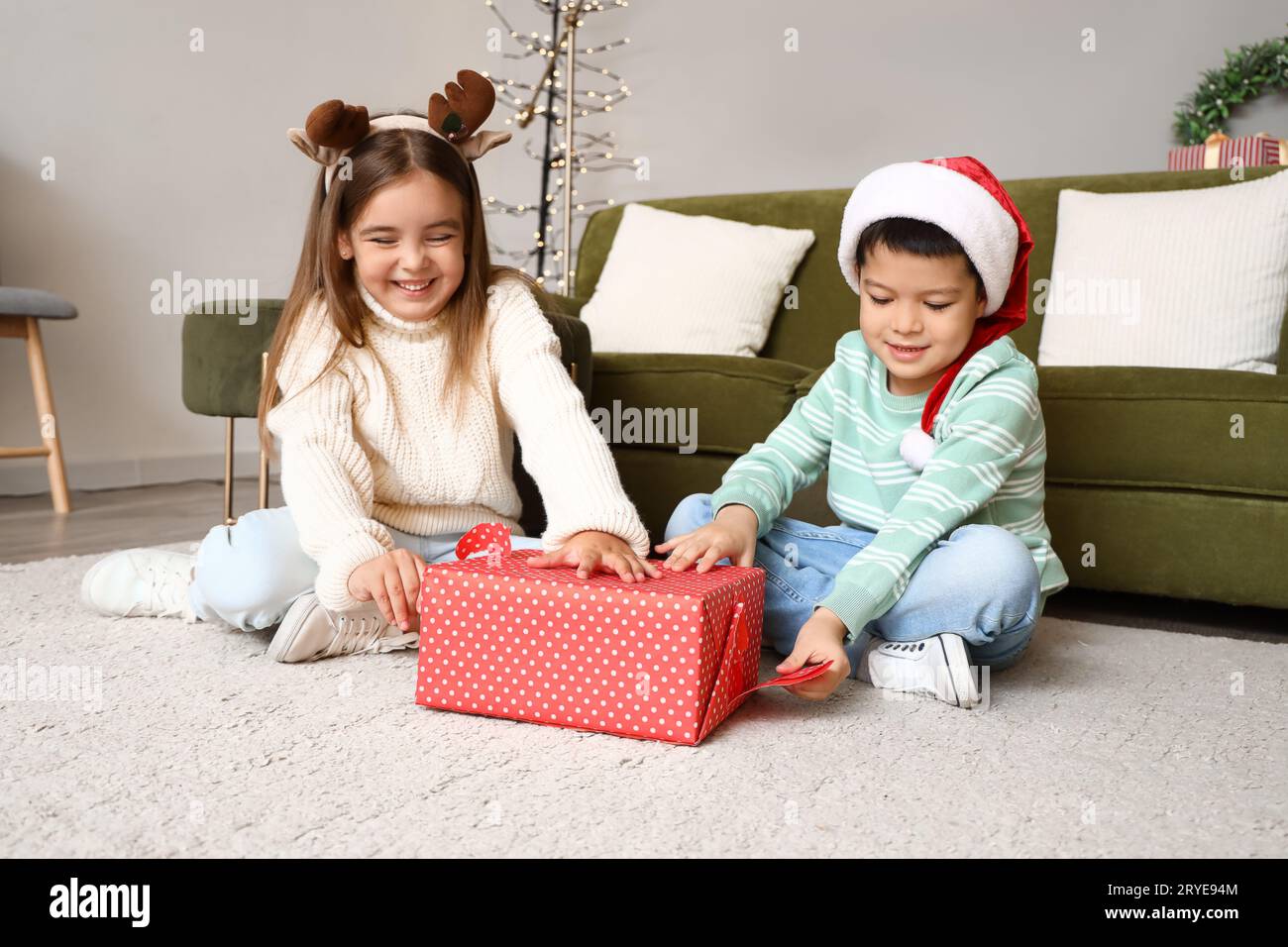 Cute little children unwrapping Christmas gift at home Stock Photo - Alamy