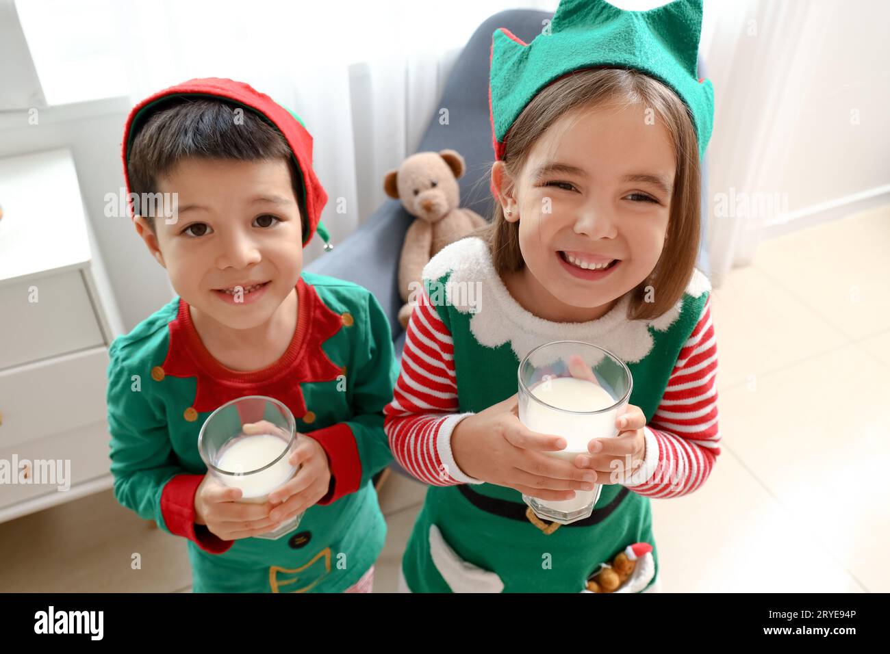 Cute little children dressed as elves with milk at home on Christmas ...