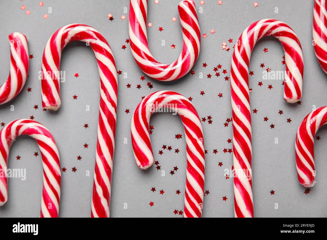 Christmas candy canes and confetti on grey background Stock Photo - Alamy
