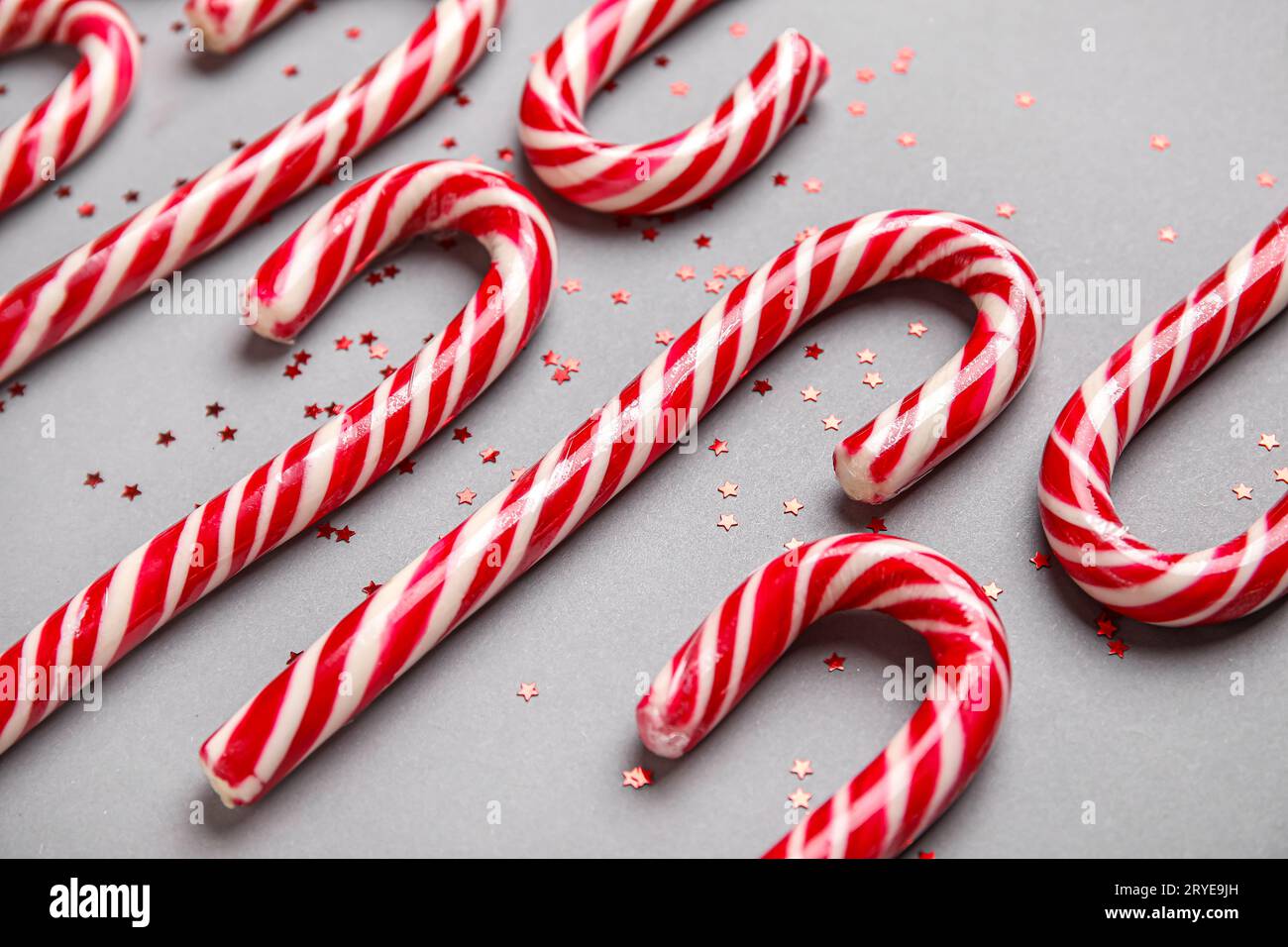 Christmas candy canes and confetti on grey background Stock Photo - Alamy