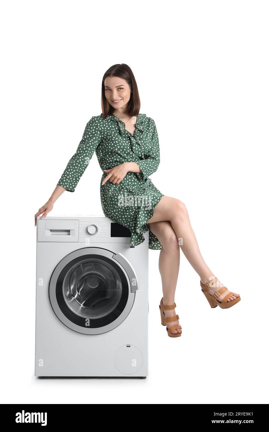Young woman sitting on washing machine against white background Stock ...