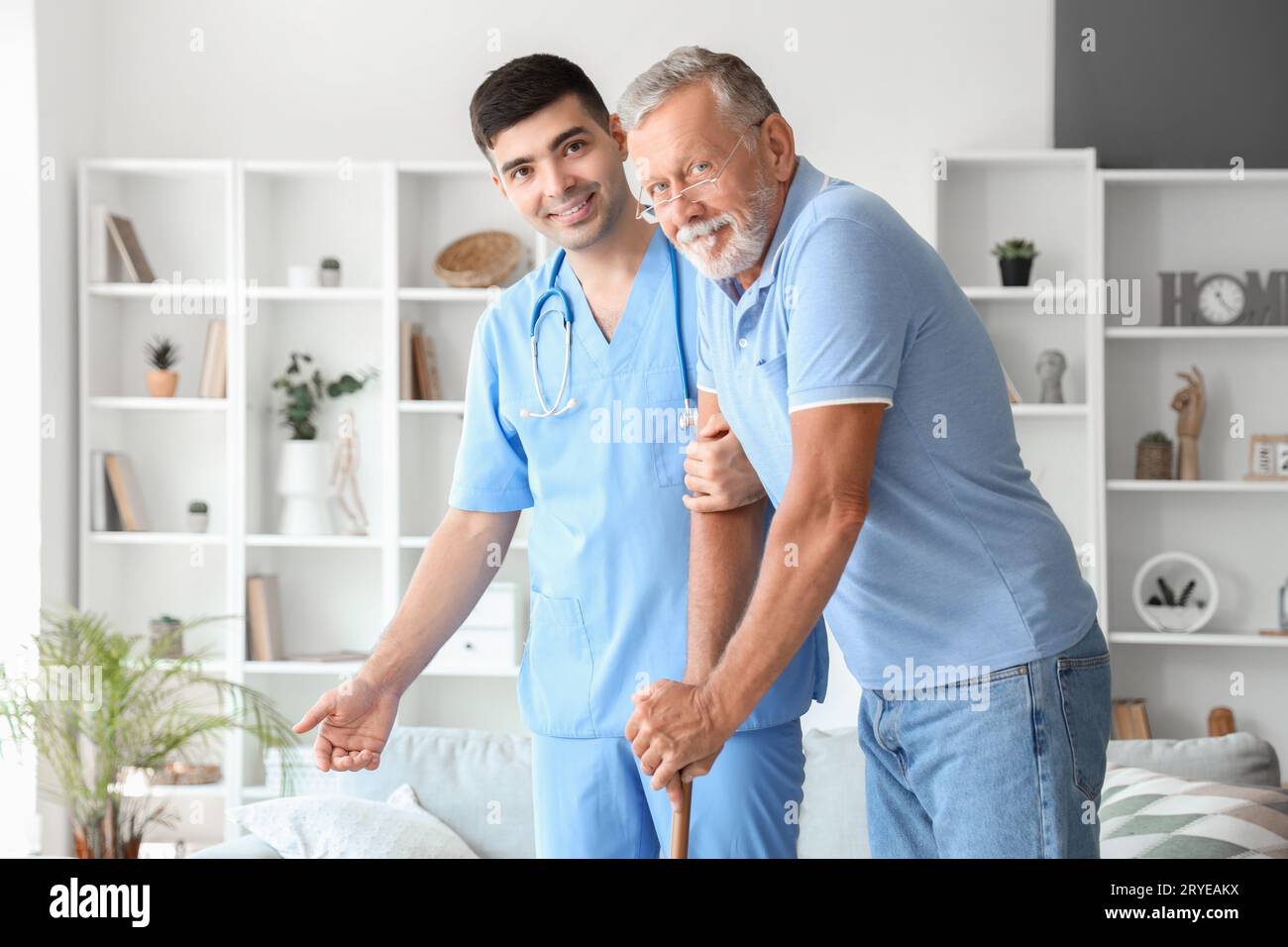 Male nurse helping senior man with stick to walk at home Stock Photo ...