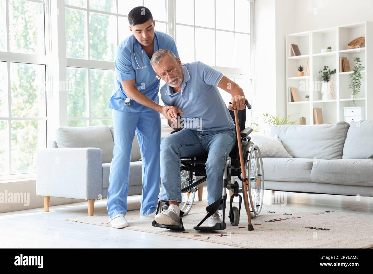 Male nurse helping senior man with stick to stand up at home Stock ...