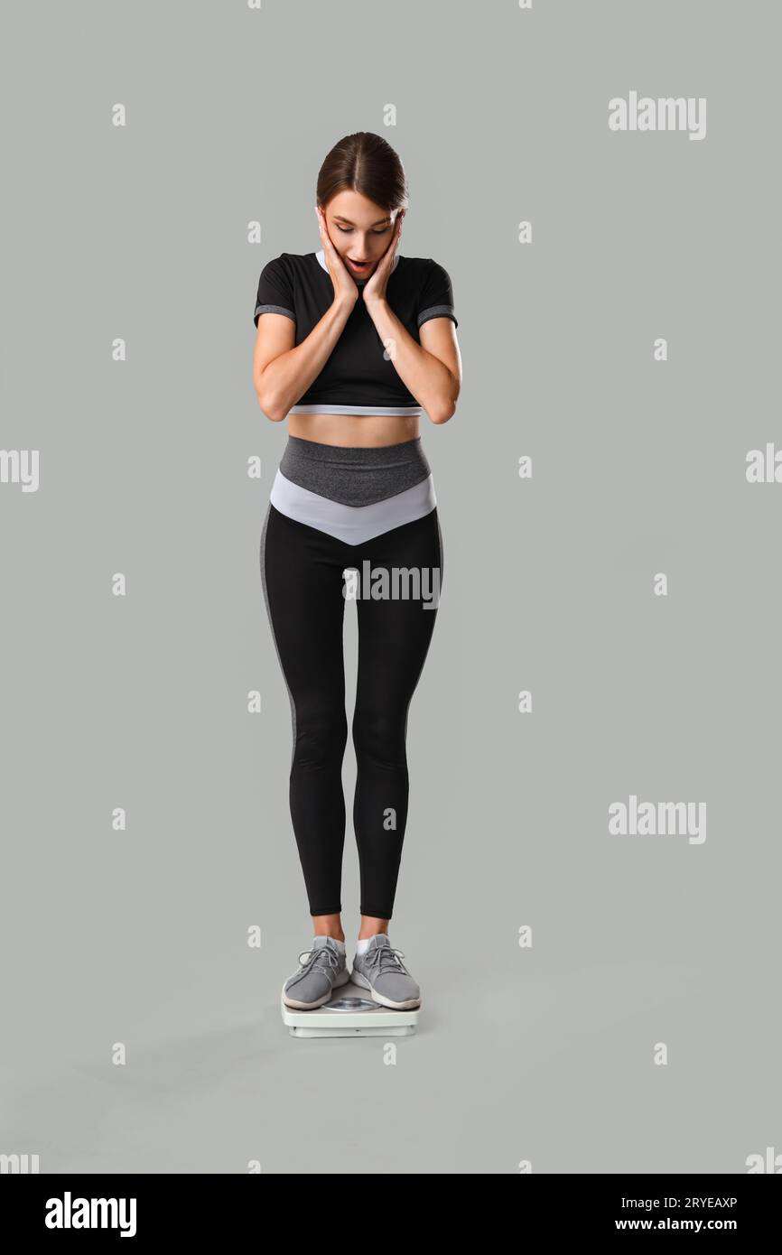 Shocked young woman with scales on grey background. Weight loss concept ...