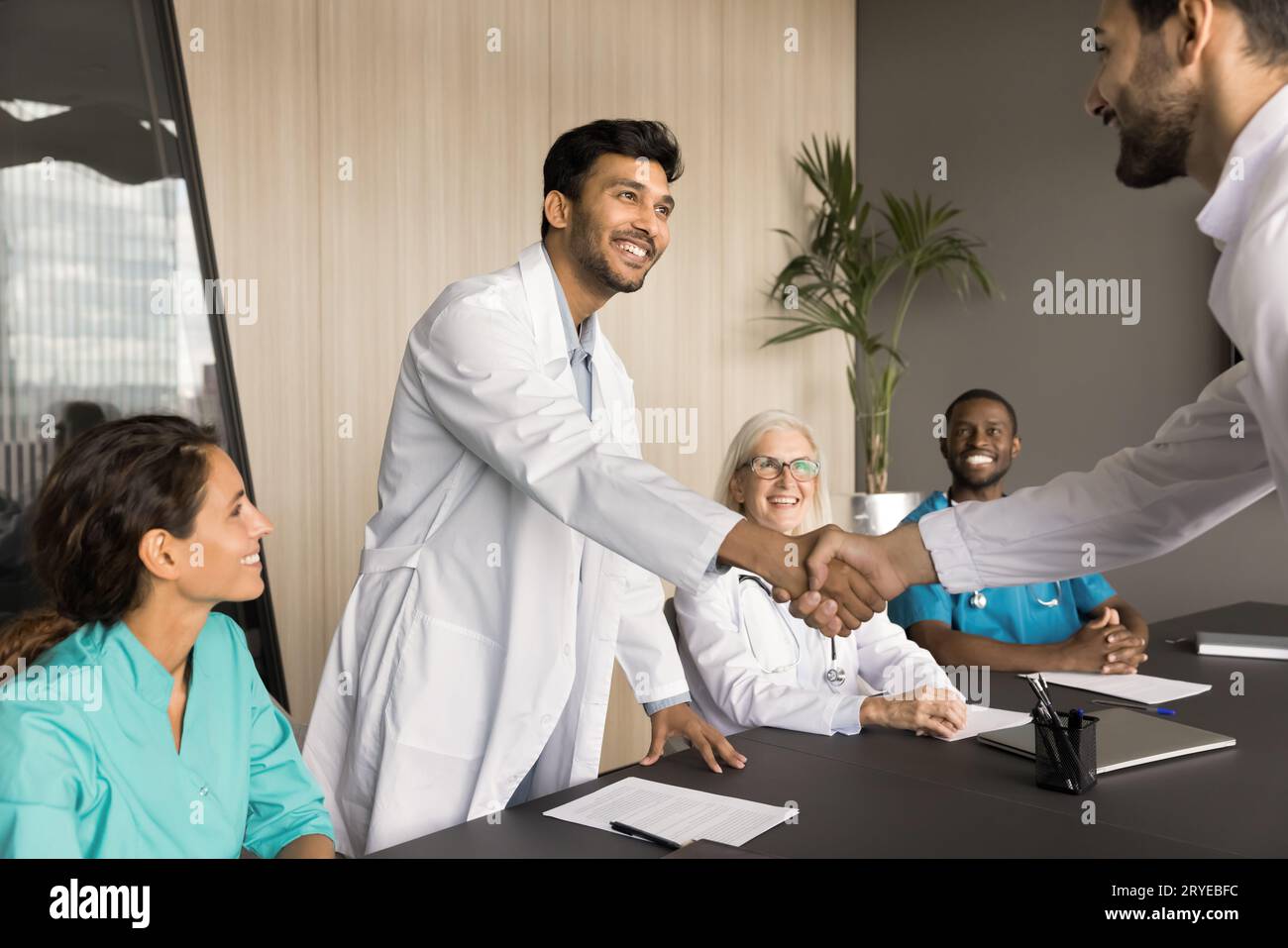 Happy young Indian male doctor giving handshake to cooperation partner ...