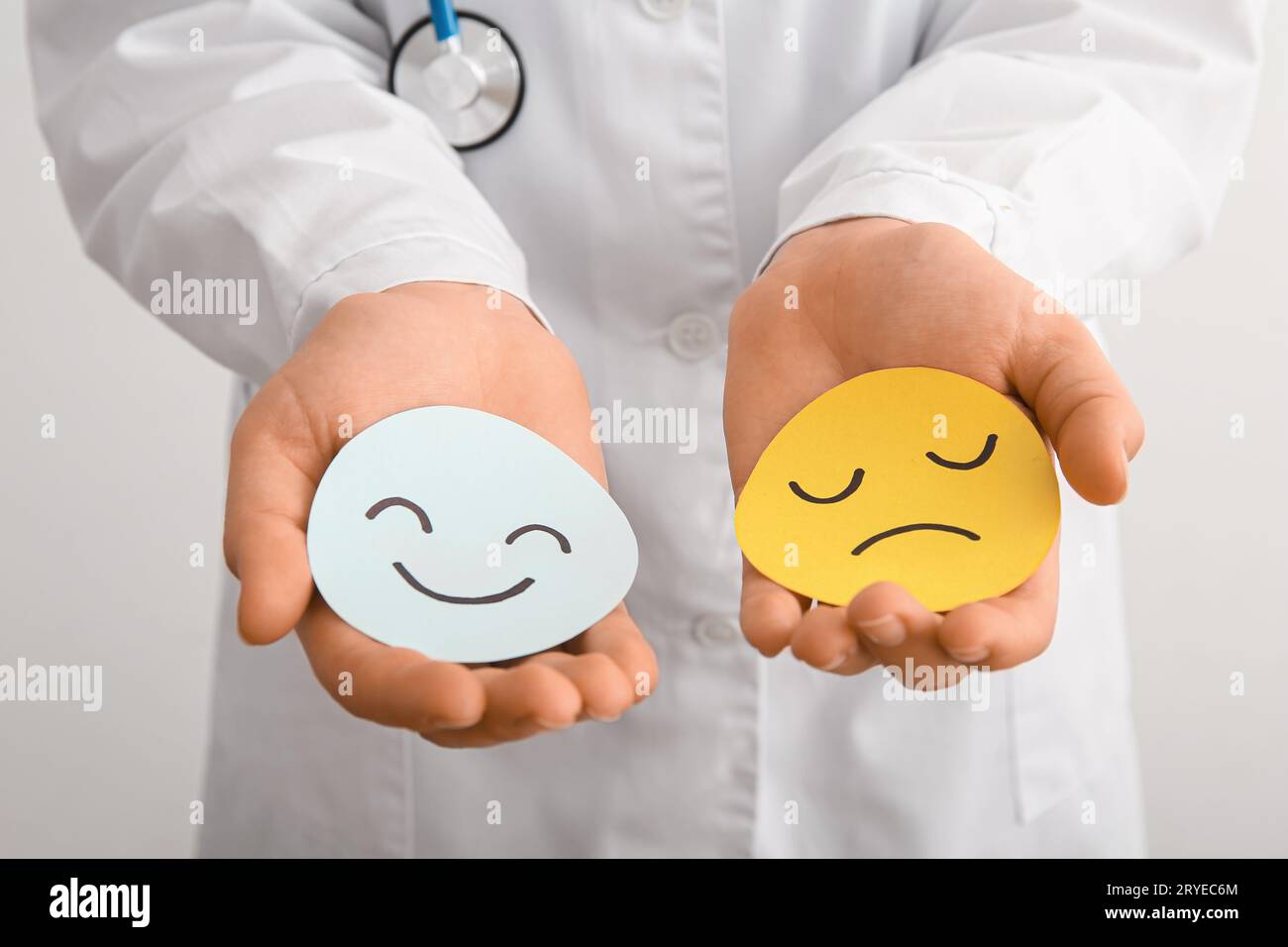 Female doctor holding paper faces with different emotions, closeup ...