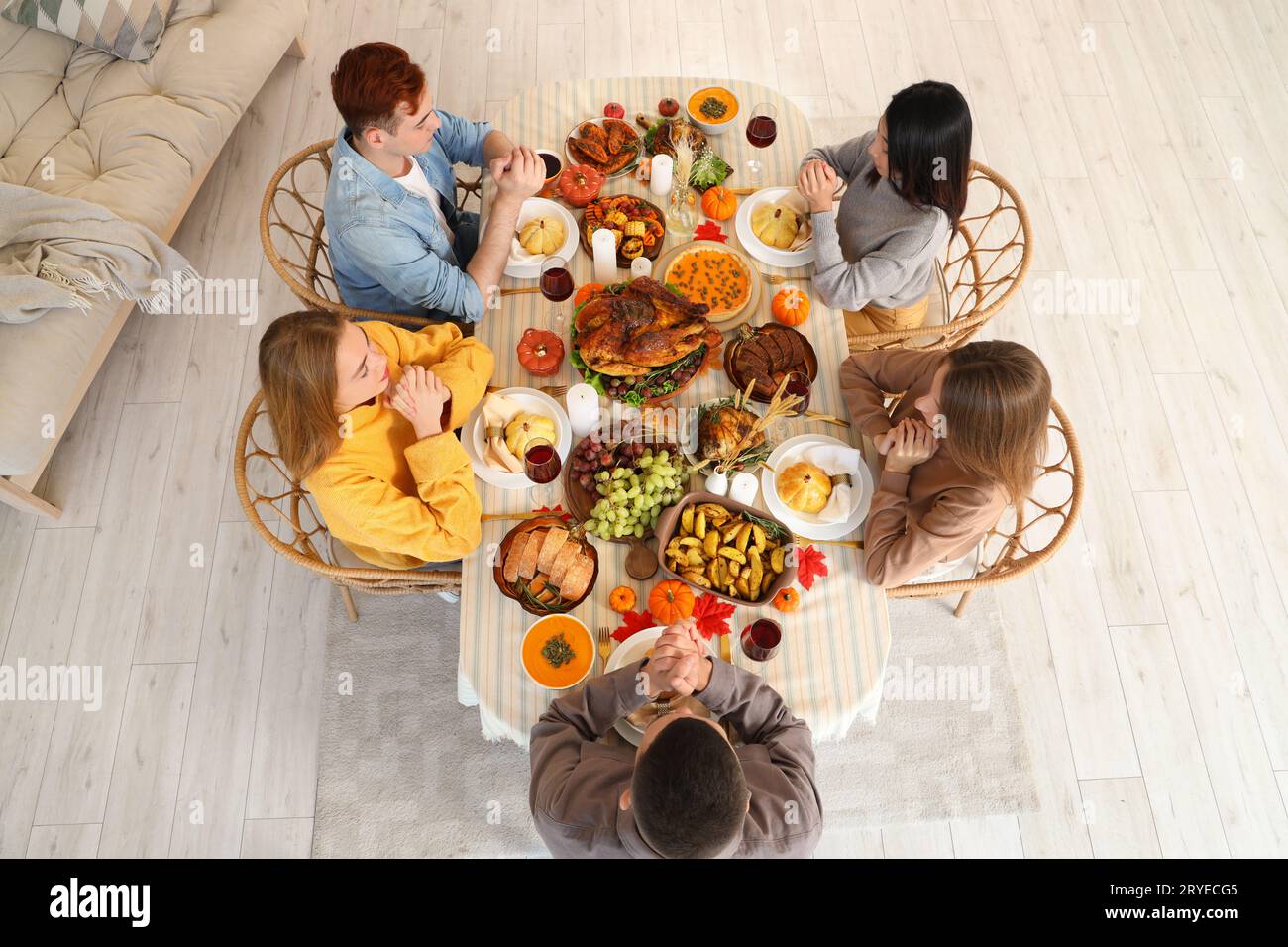 Group of young friends praying before dinner at festive table on ...