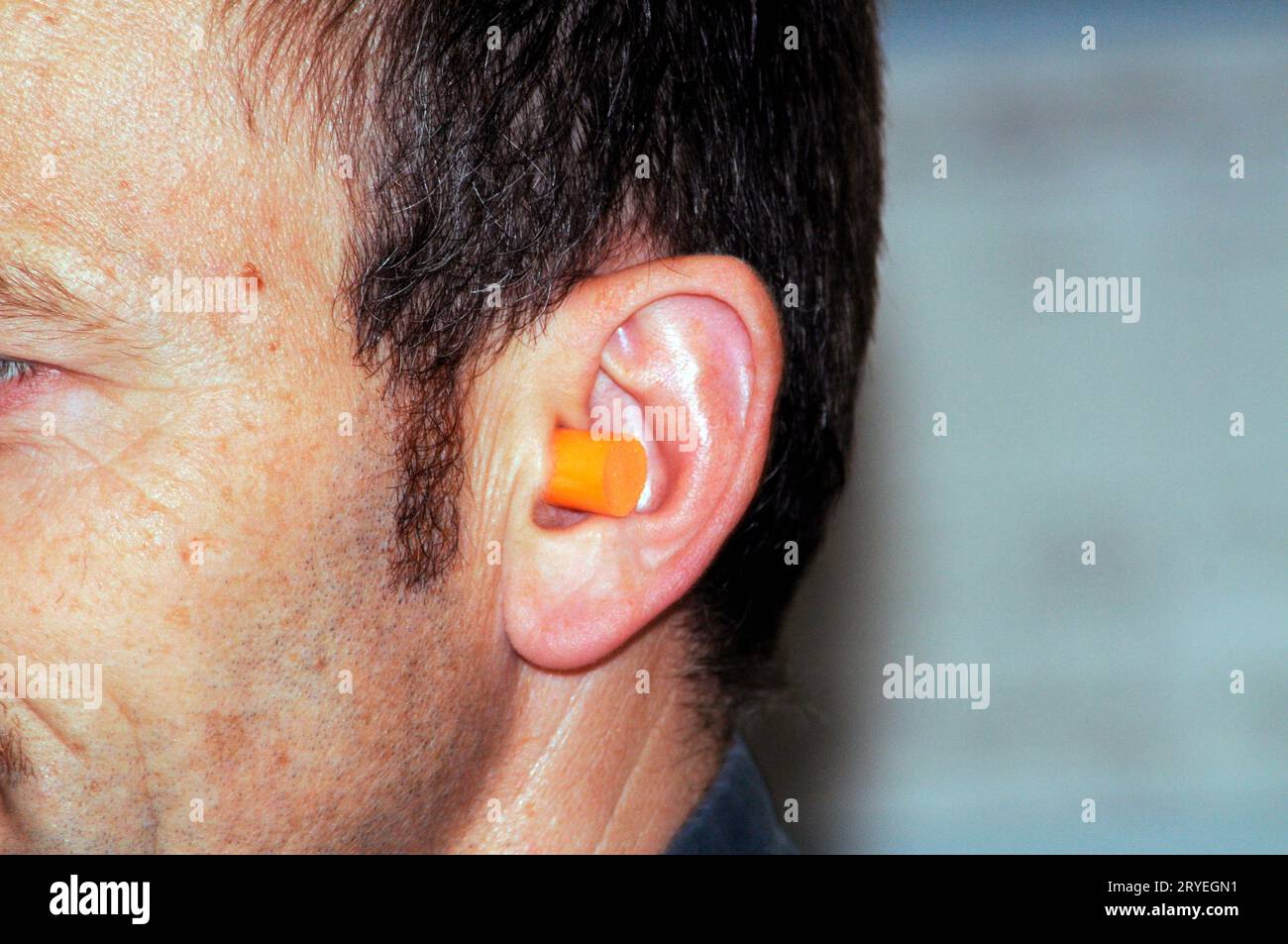 Man wearing an orange earplug Stock Photo - Alamy