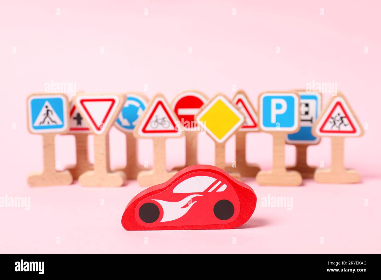 Set of wooden road signs and car on light pink background. Children's ...