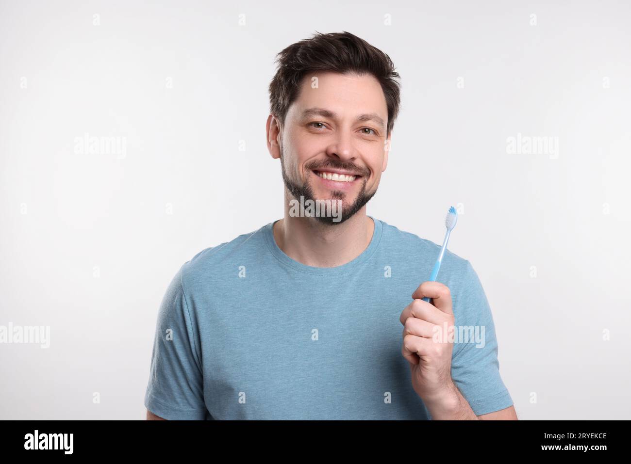 Happy man holding plastic toothbrush on white background. Mouth hygiene ...