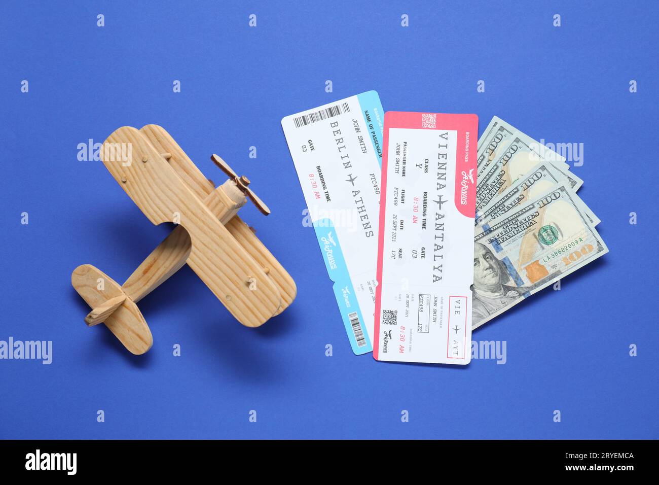 Dollars, wooden model of plane and tickets on blue table, flat lay ...