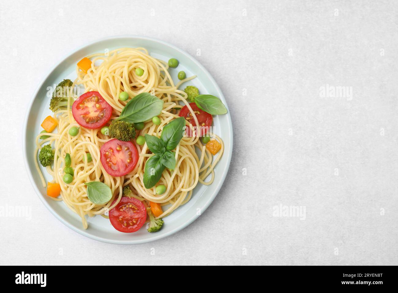 Plate of delicious pasta primavera on light gray table, top view. Space ...
