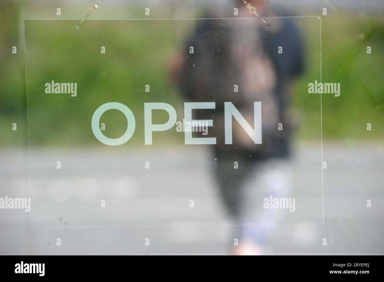 Open sign with blurred out person in background Stock Photo - Alamy