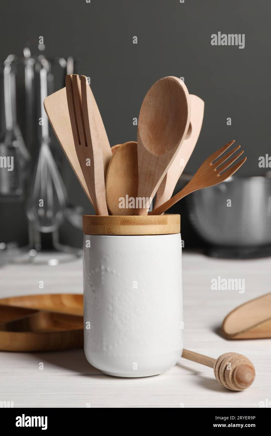 Set of different kitchen utensils on white wooden table against grey ...