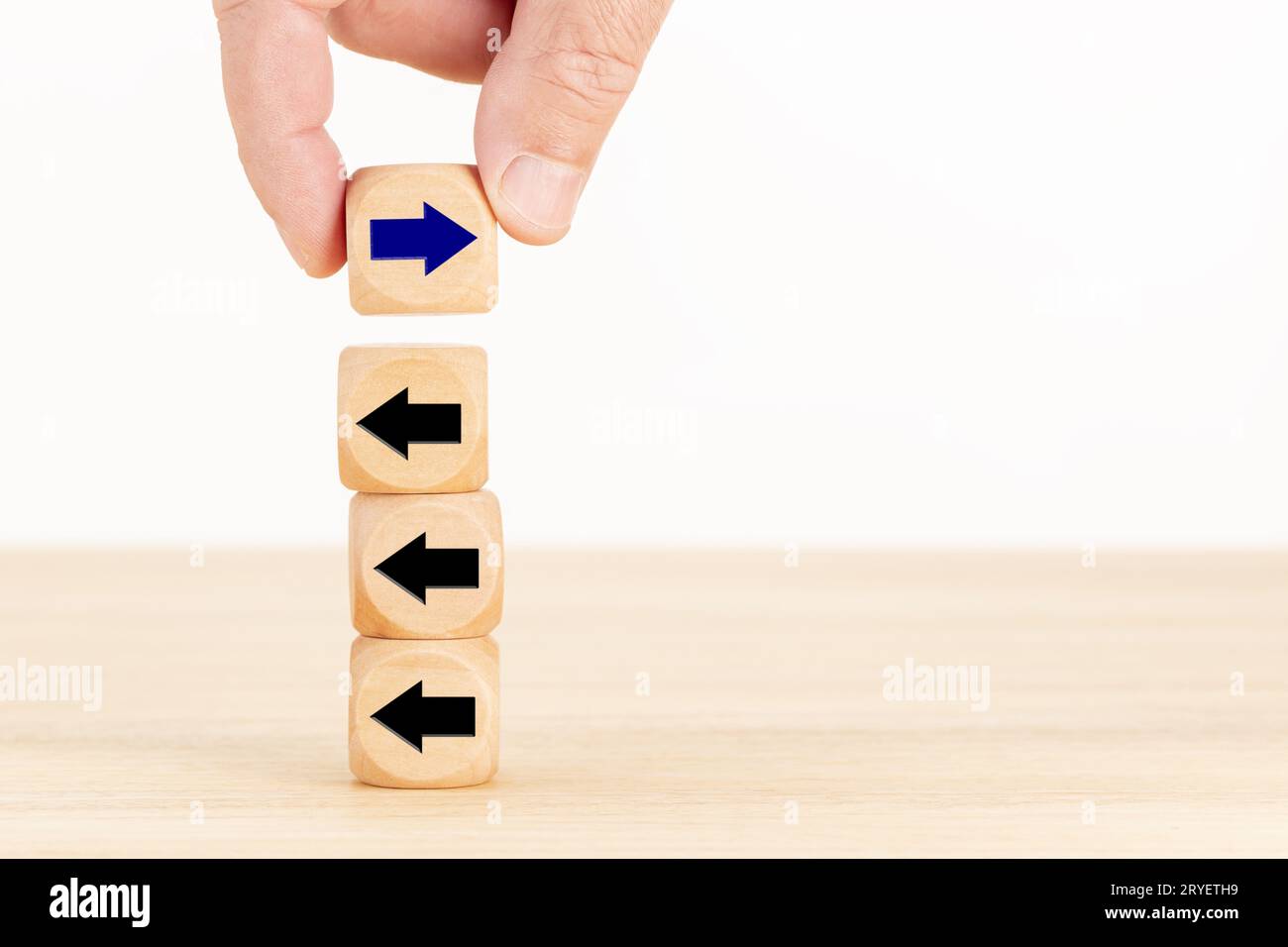 Hand holding a wooden block with Arrow icon on opposite direction to ...