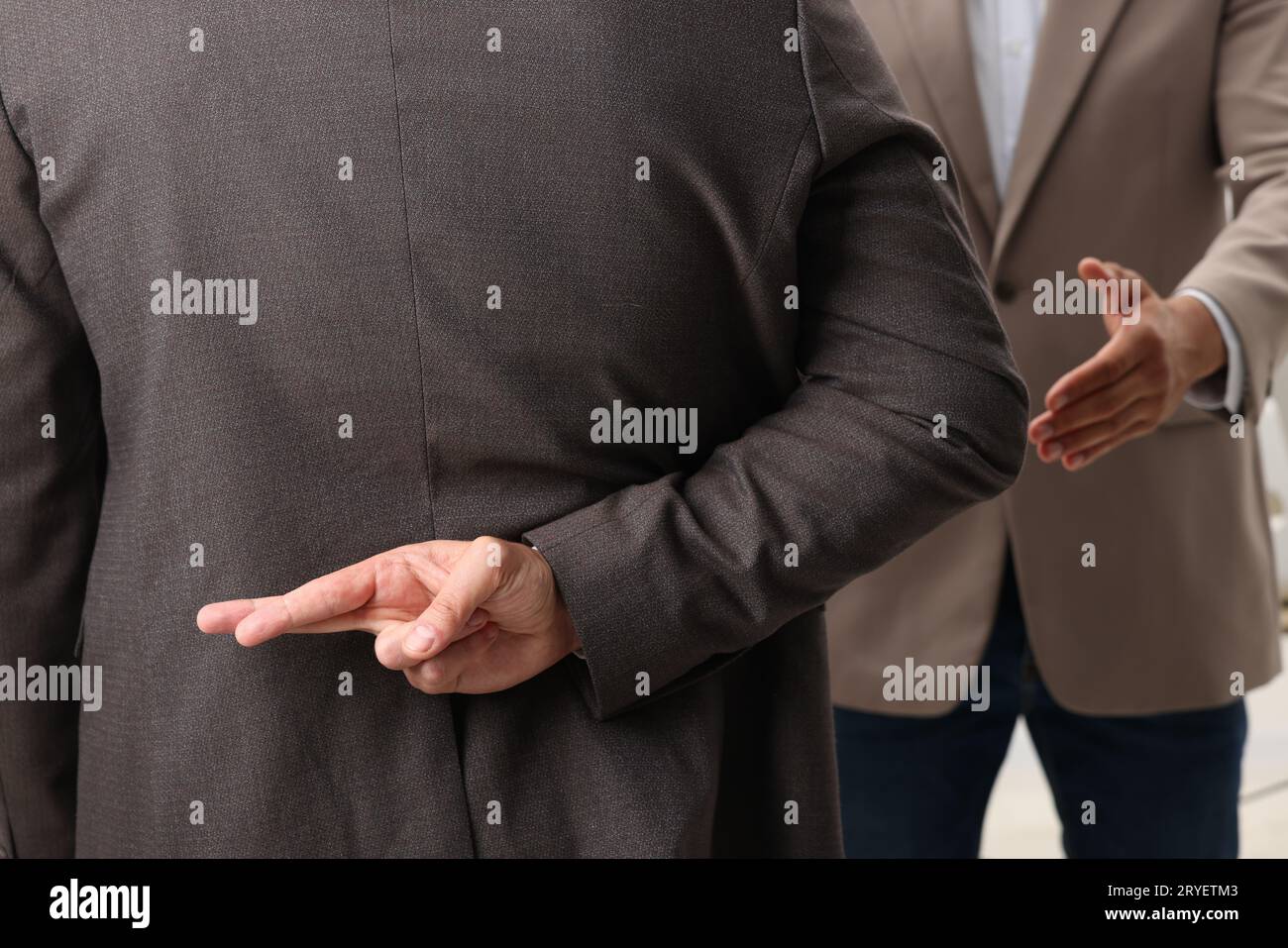 Employee crossing fingers behind his back while meeting with boss ...