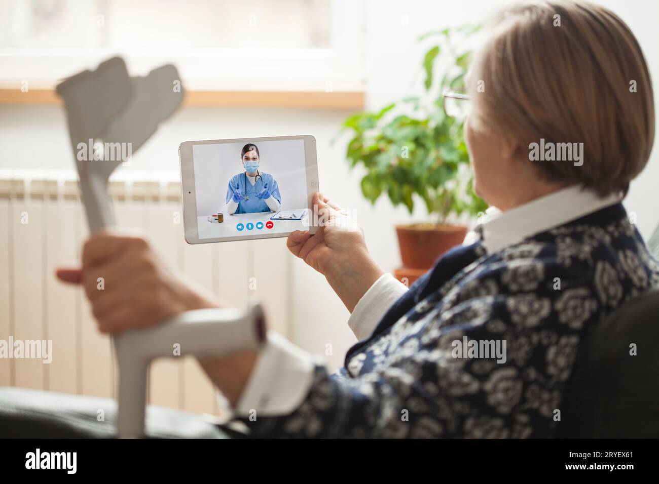 Retired senior elderly woman holding crutch and tablet computer talking ...