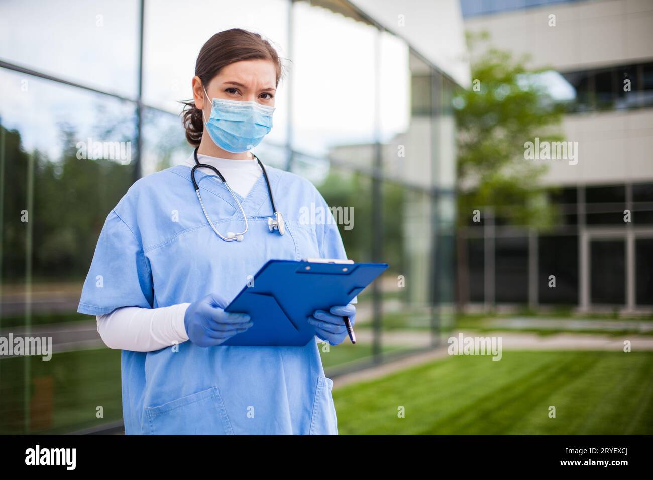 Portrait of tired exhausted female caucasian NHS UK EMS doctor in front ...