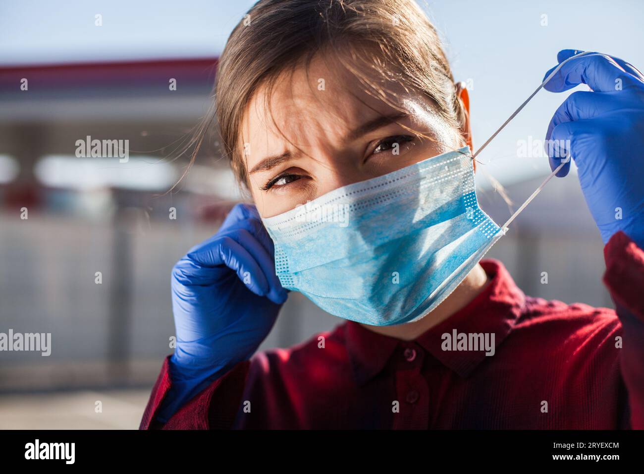 Worried young woman putting PPE face mask on/taking it off in public ...