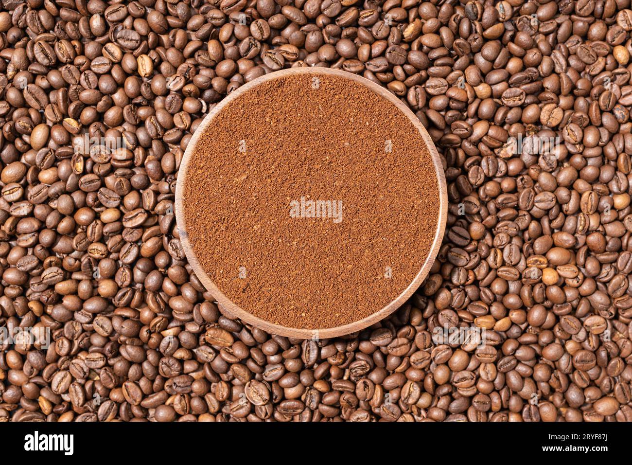 Ground coffee in wooden plate on coffee beans background. Top view ...