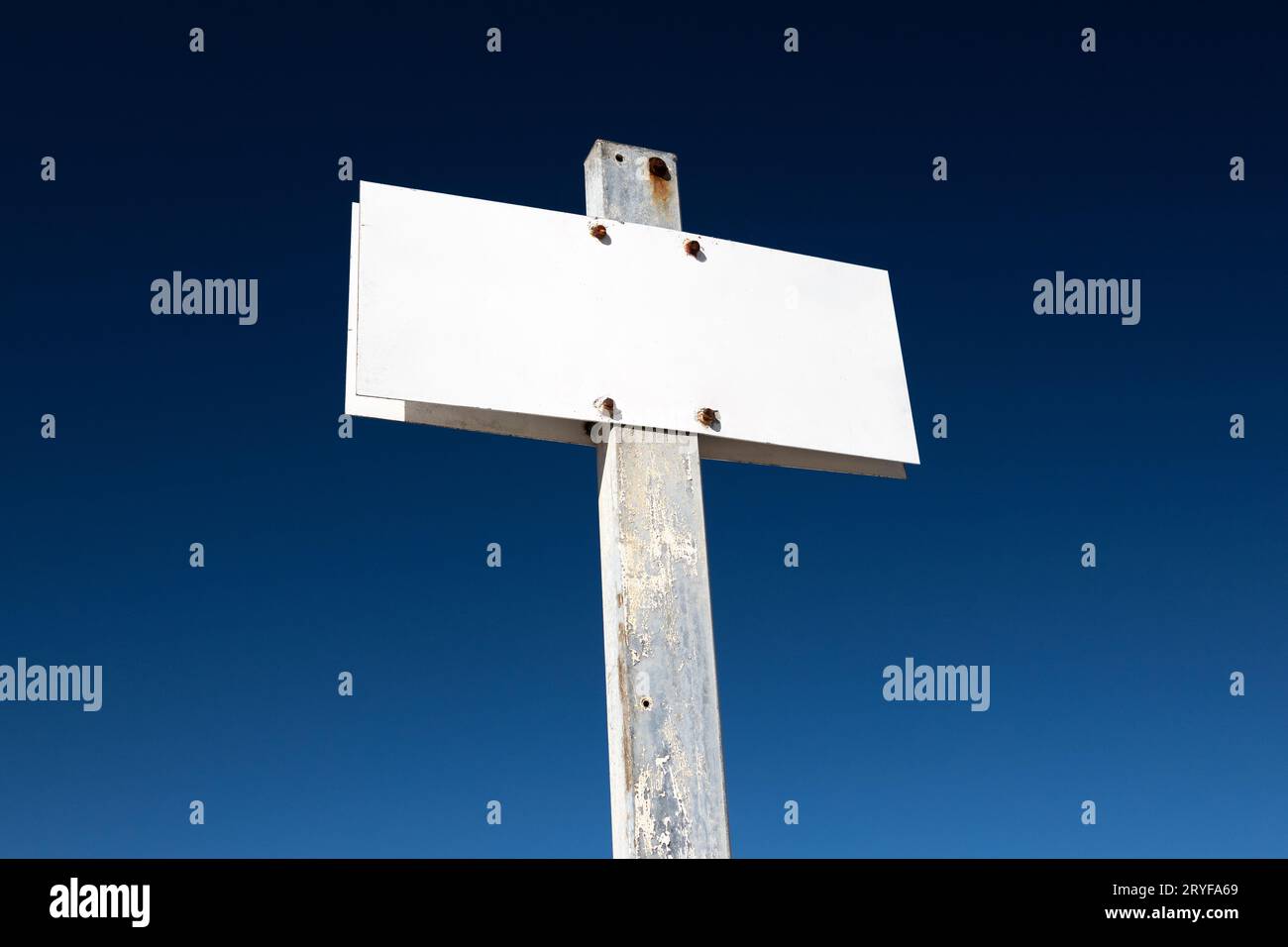 Blank white sign isolated on dramatic blue sky. Aged metallic post sign ...
