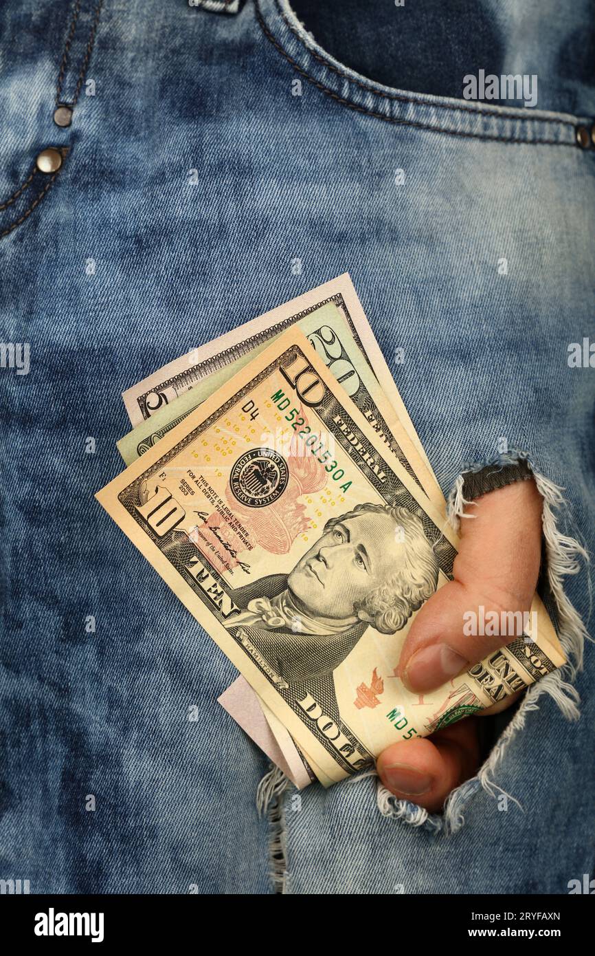 Hand holds US dollar banknotes in jeans rip hole Stock Photo - Alamy