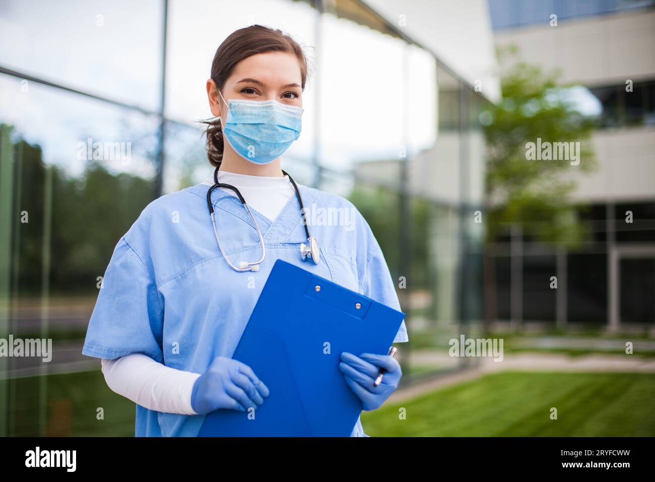 Portrait of beautiful young female doctor wearing blue protective ...