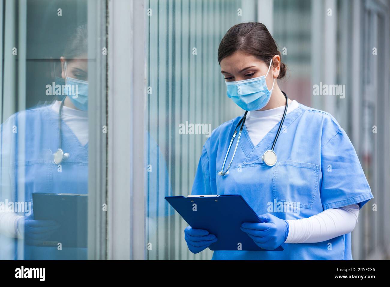 Worried young female caucasian NHS UK doctor holding clipboard,standing ...
