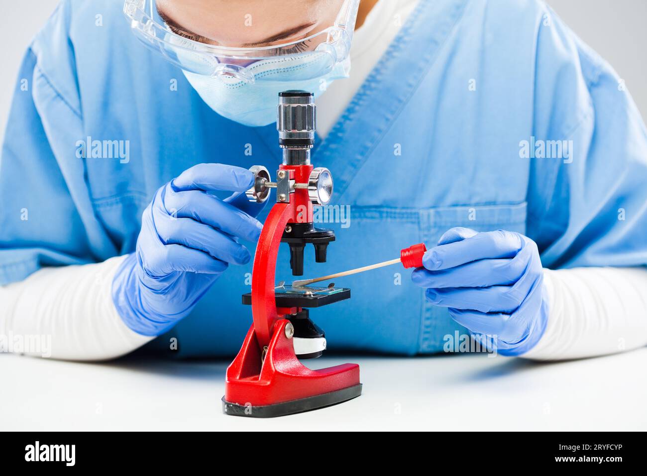 Female scientist studying cotton swab sample specimen under microscope ...