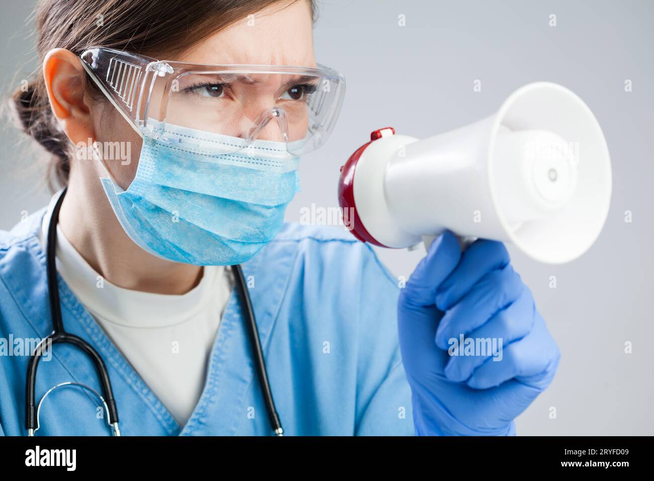 Woman doctor shouting over megaphone wearing face mask and protective ...