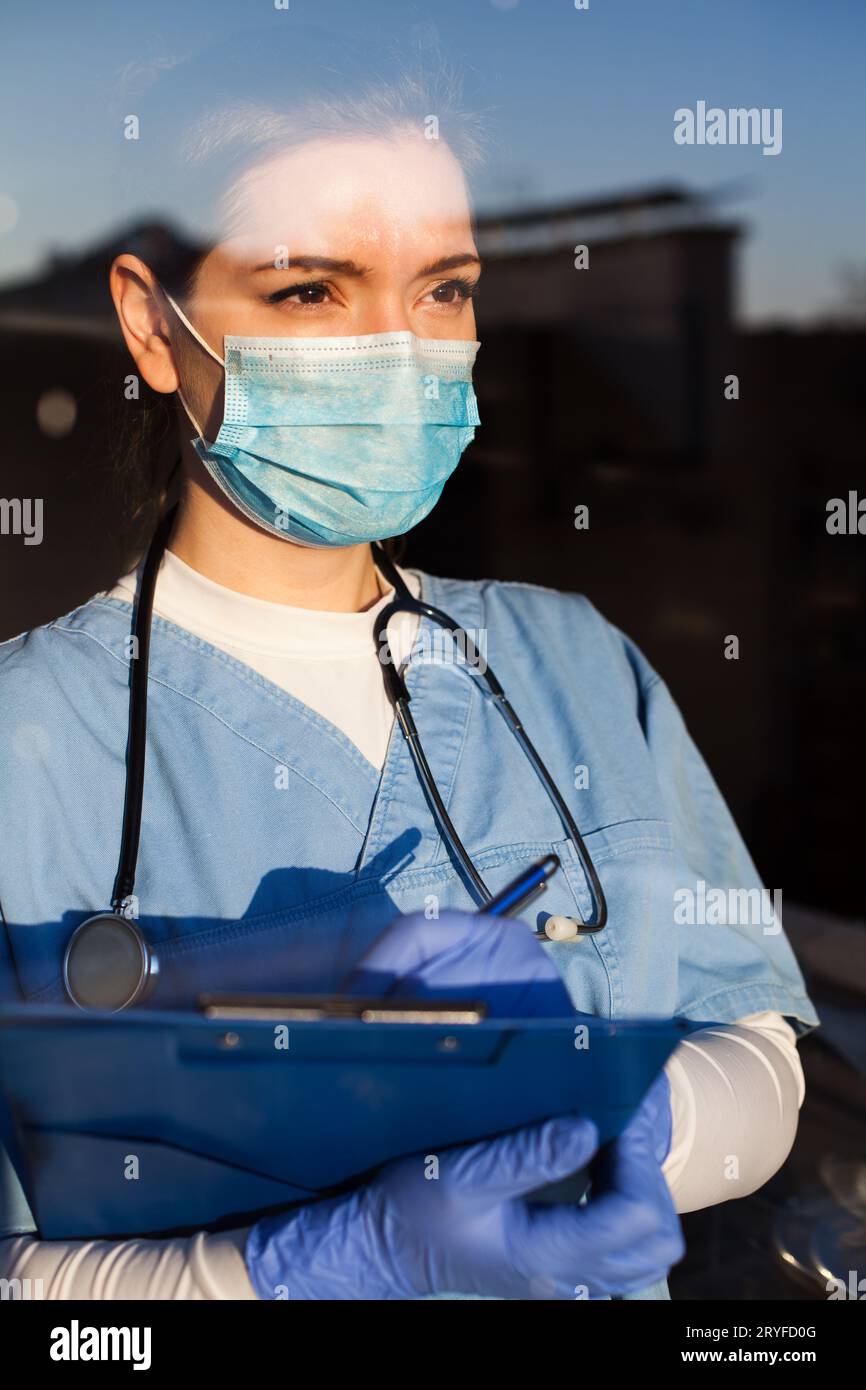Portrait of young female doctor looking through hospital window Stock ...