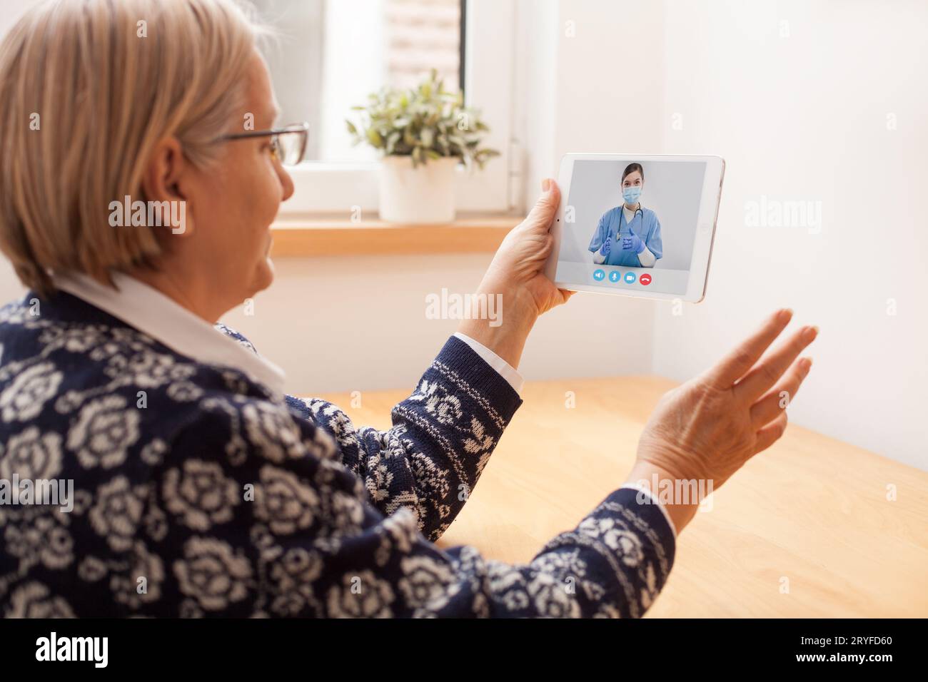 Elderly female patient talking to young female doctor via video call ...