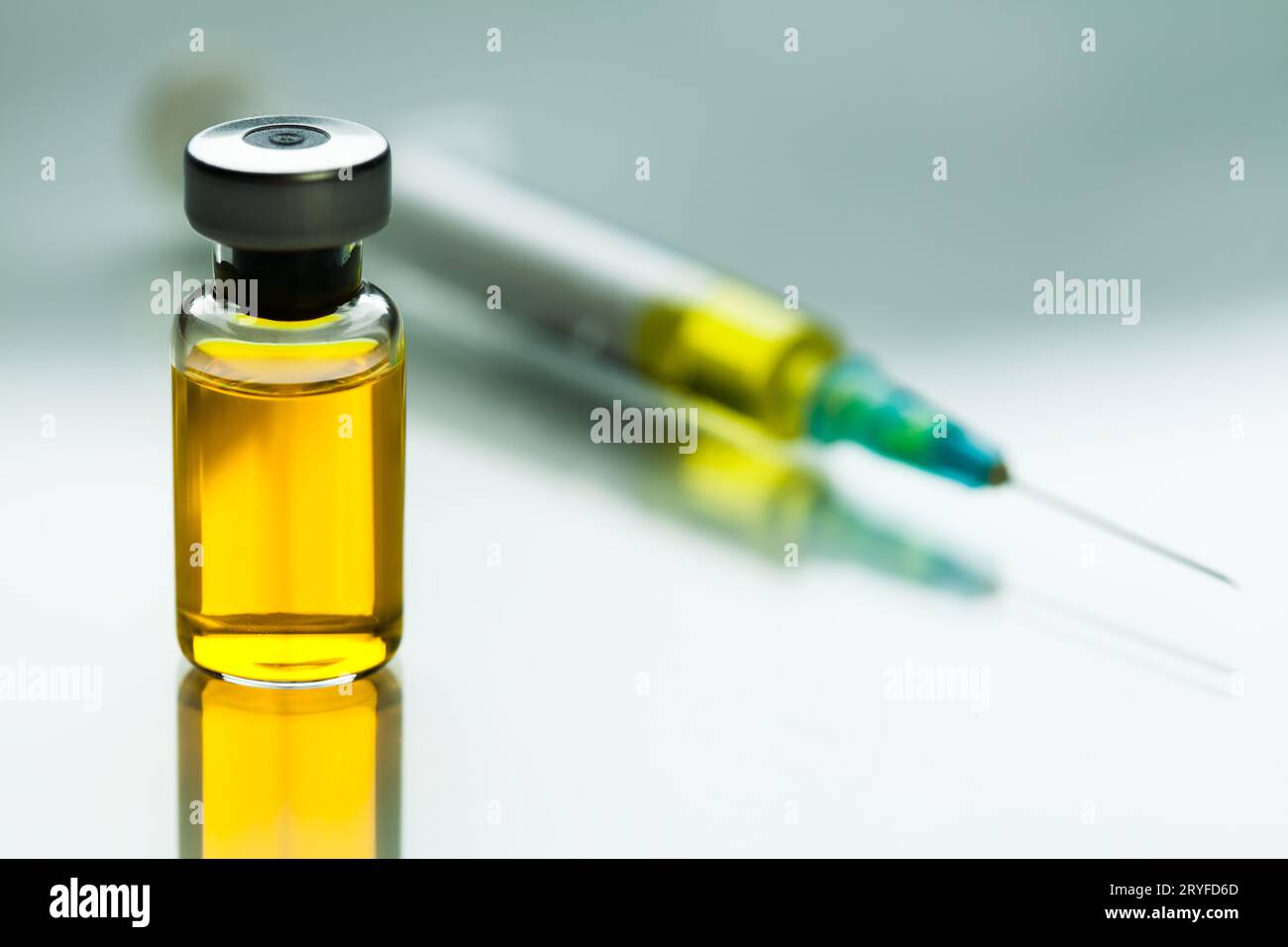 Yellow liquid in glass ampoule vial next to syringe with needle Stock ...