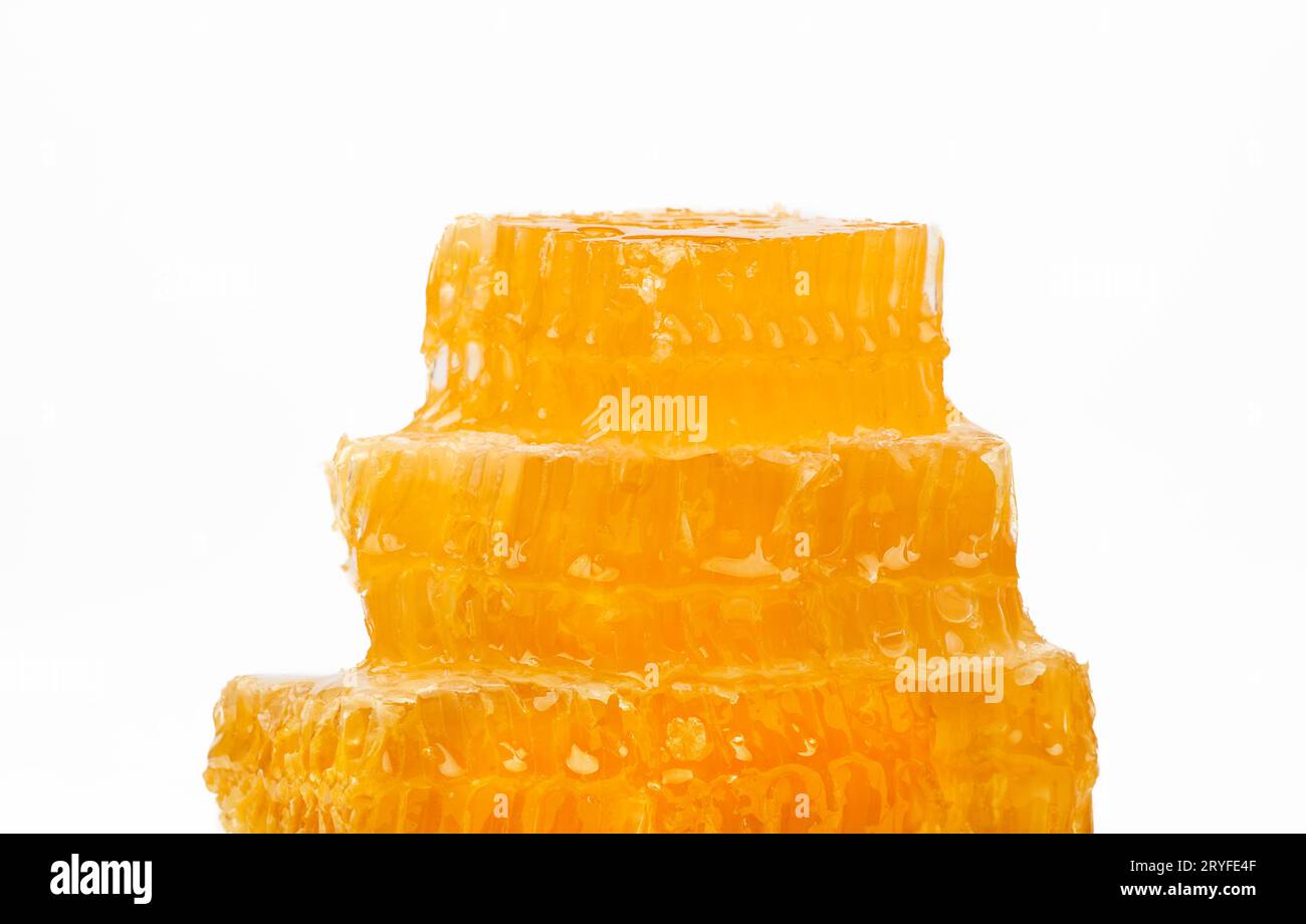 Close up stack of several fresh cut golden comb honey slices on plate ...