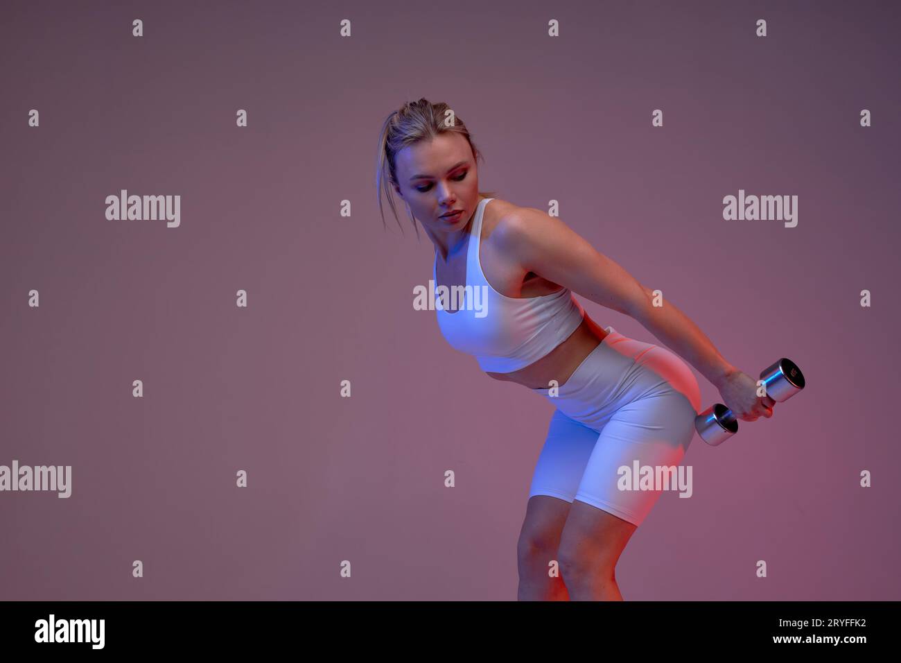 Awesome Sporty Girl Bending Her Back Toward Looking Back At Dumbbells