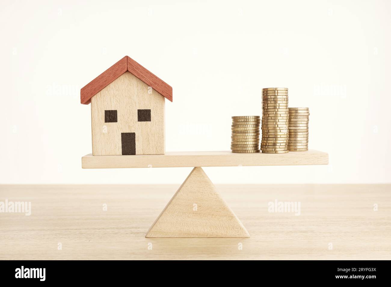 House and money put on wooden scale with balance. Property investment ...