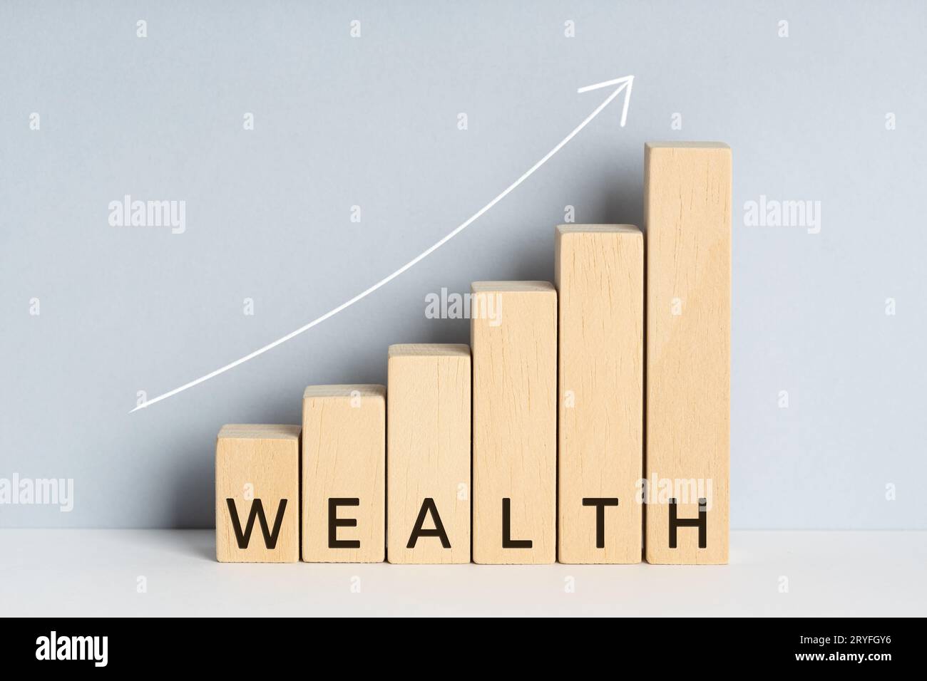 Wealth concept. Wooden block bar chart graph with text and upward trend line drawn on background ...