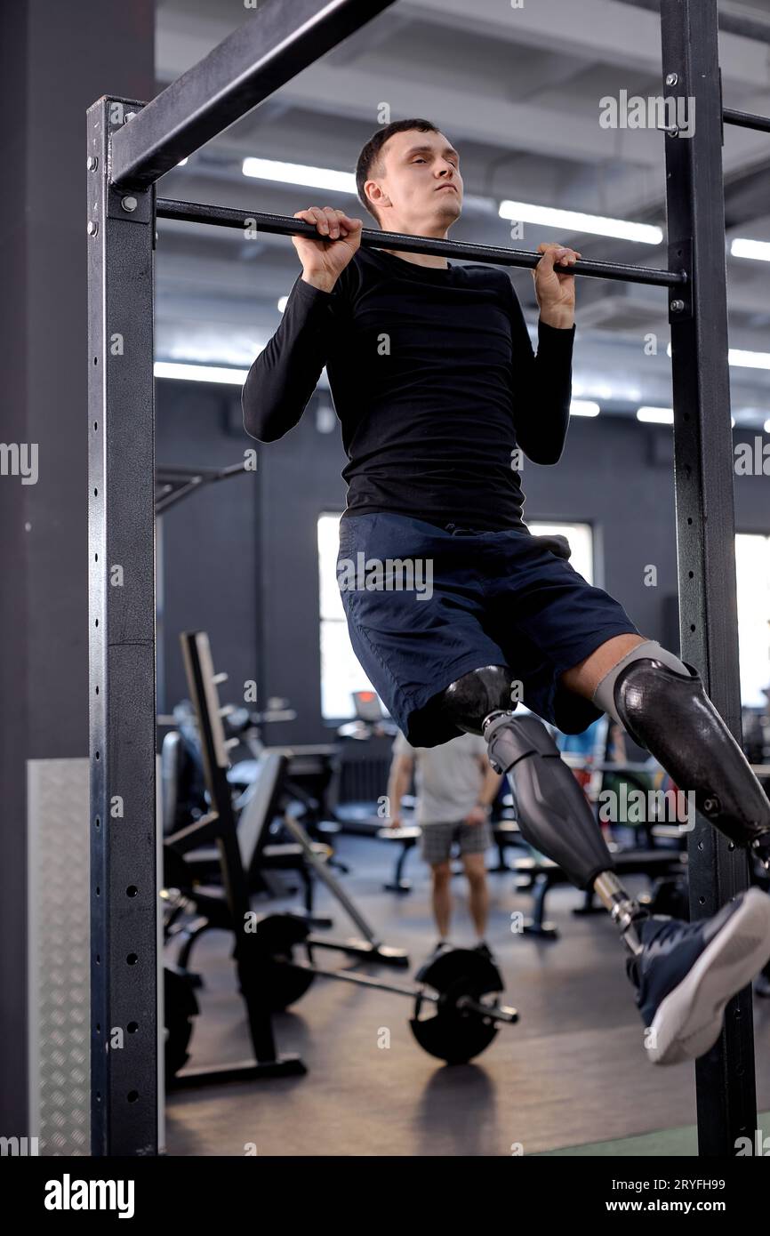 young motivated serious man building upper body strength, hanging on ...