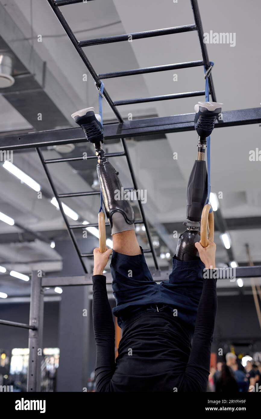 strong man hanging upside down holding rings with hands balancing body ...