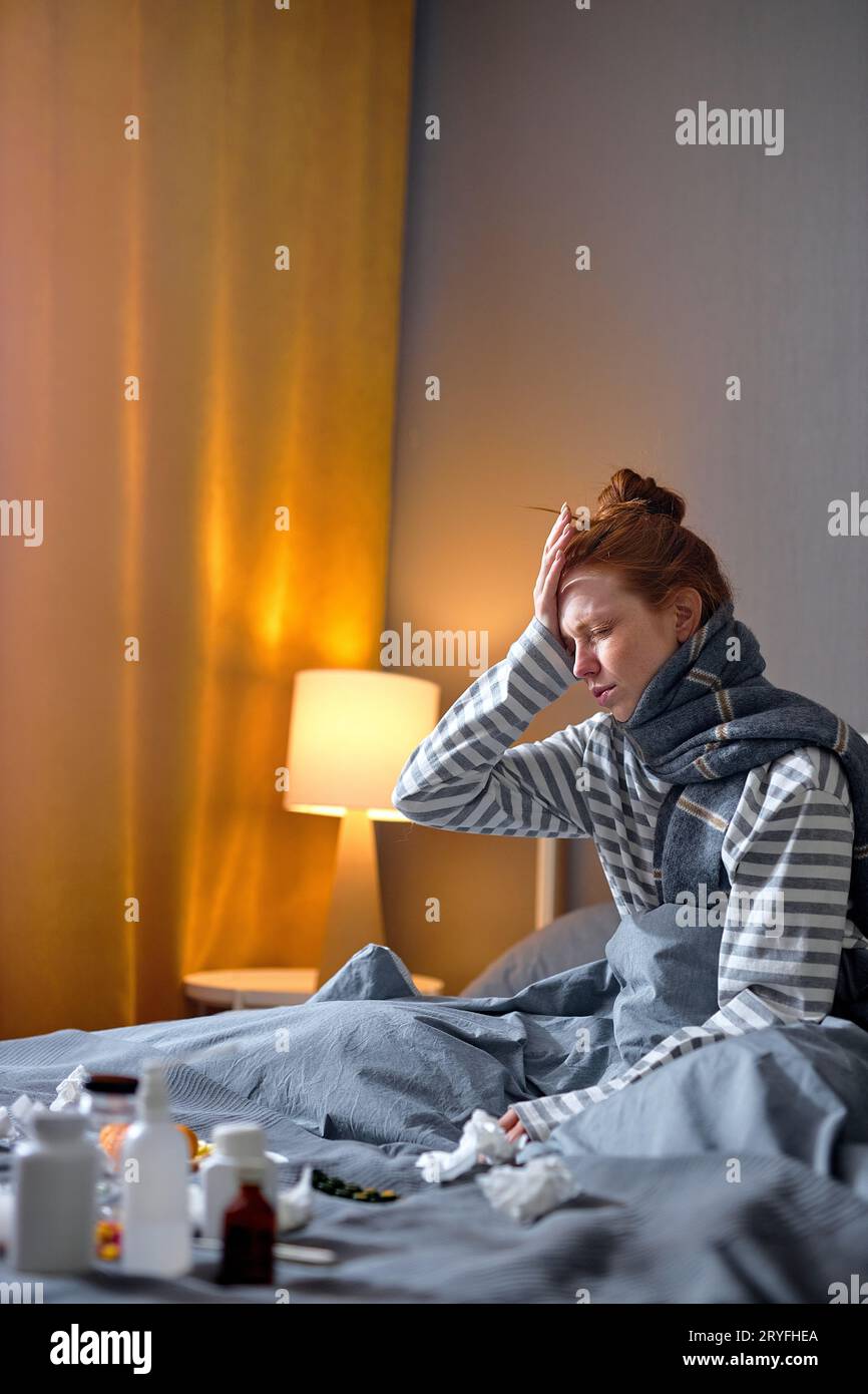young exhausted sleepy woman sitting on the bed in her room with a ...