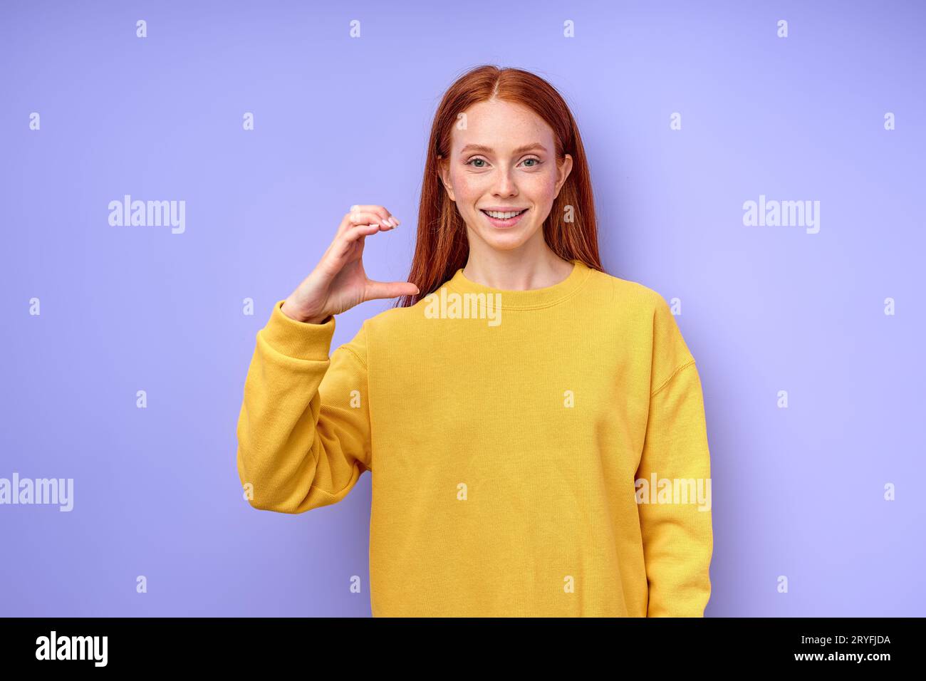 Young smiling red-haired deaf woman wearing yellow sweater using sign ...