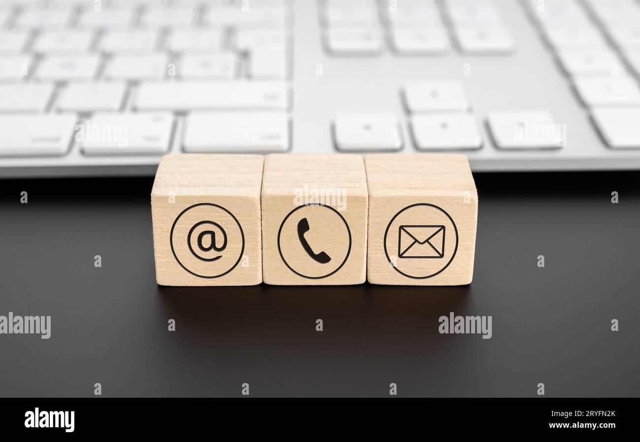Contact us icons on wooden blocks and computer keyboard on black desk ...