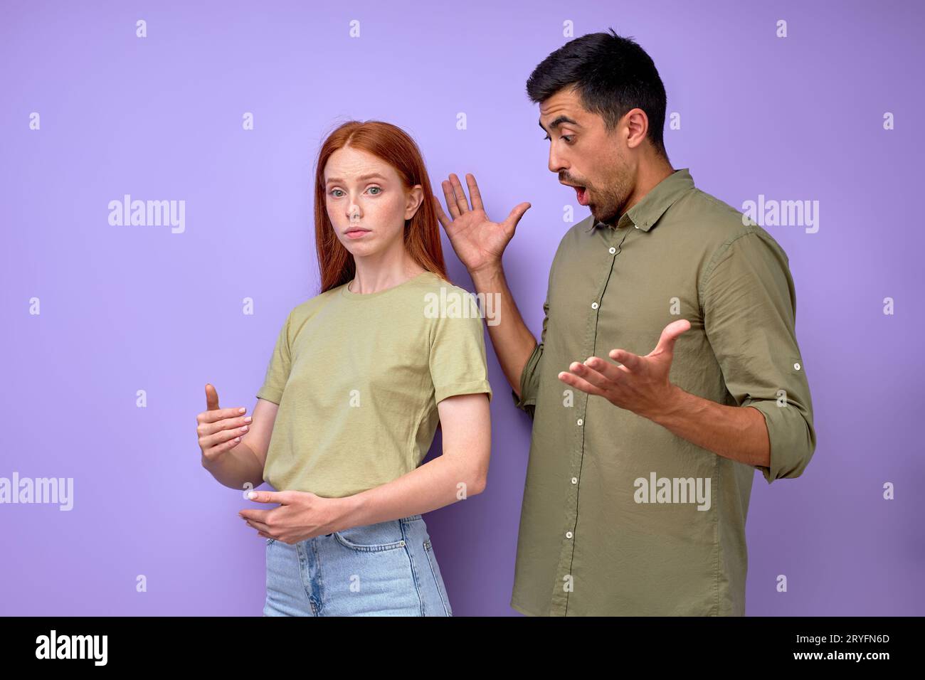 deaf mute red-haired woman saying her boyfriend that she is pregnant, man with raised arms is ...