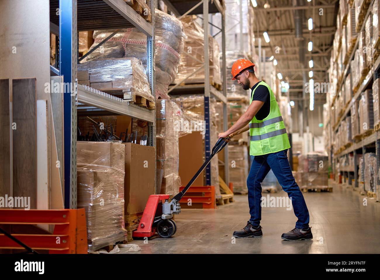 Young male warehouse worker carrying delivery to production stock using ...