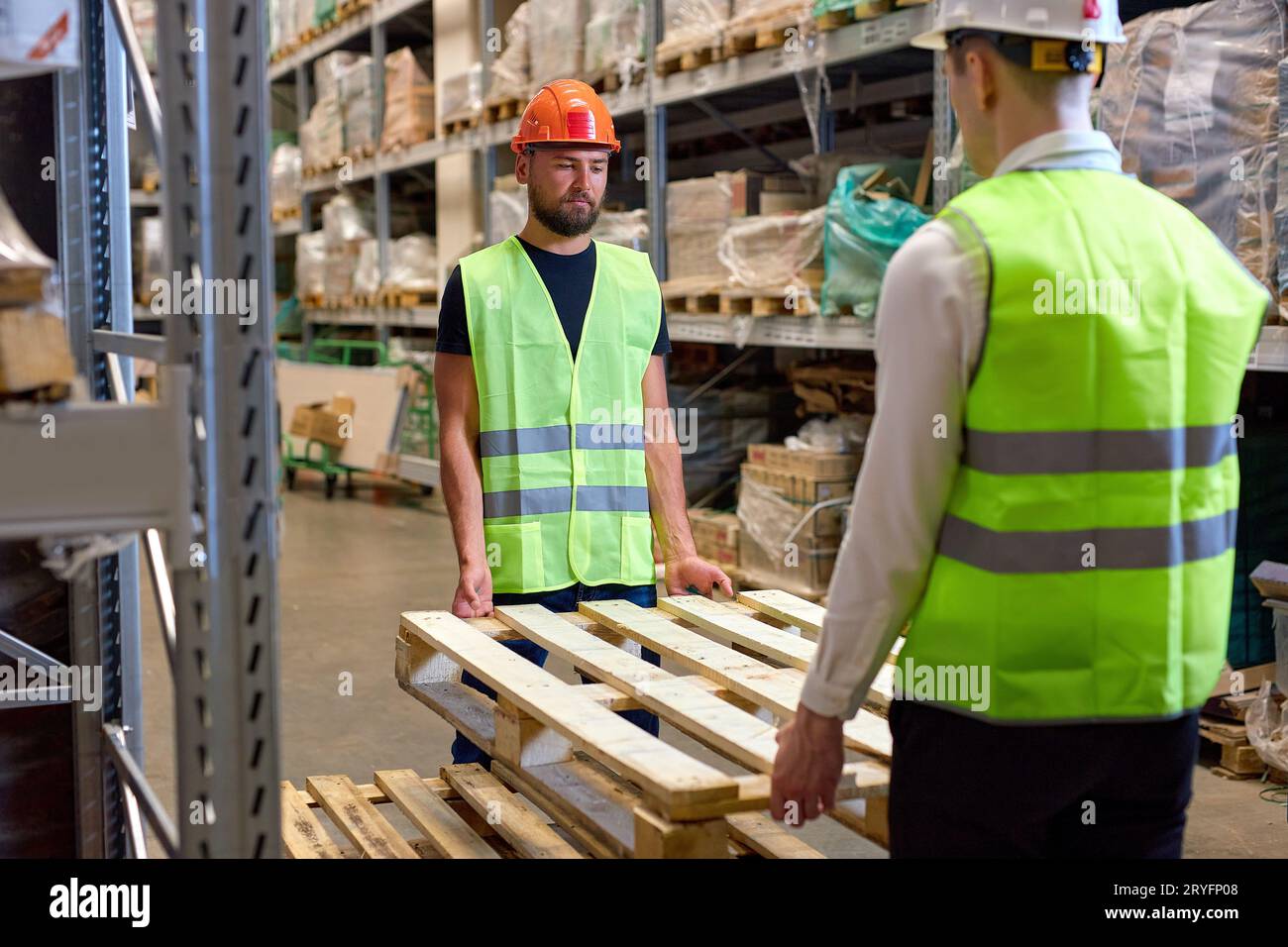 caucasian warehouse men hold cargo pallet together with co-worker in ...