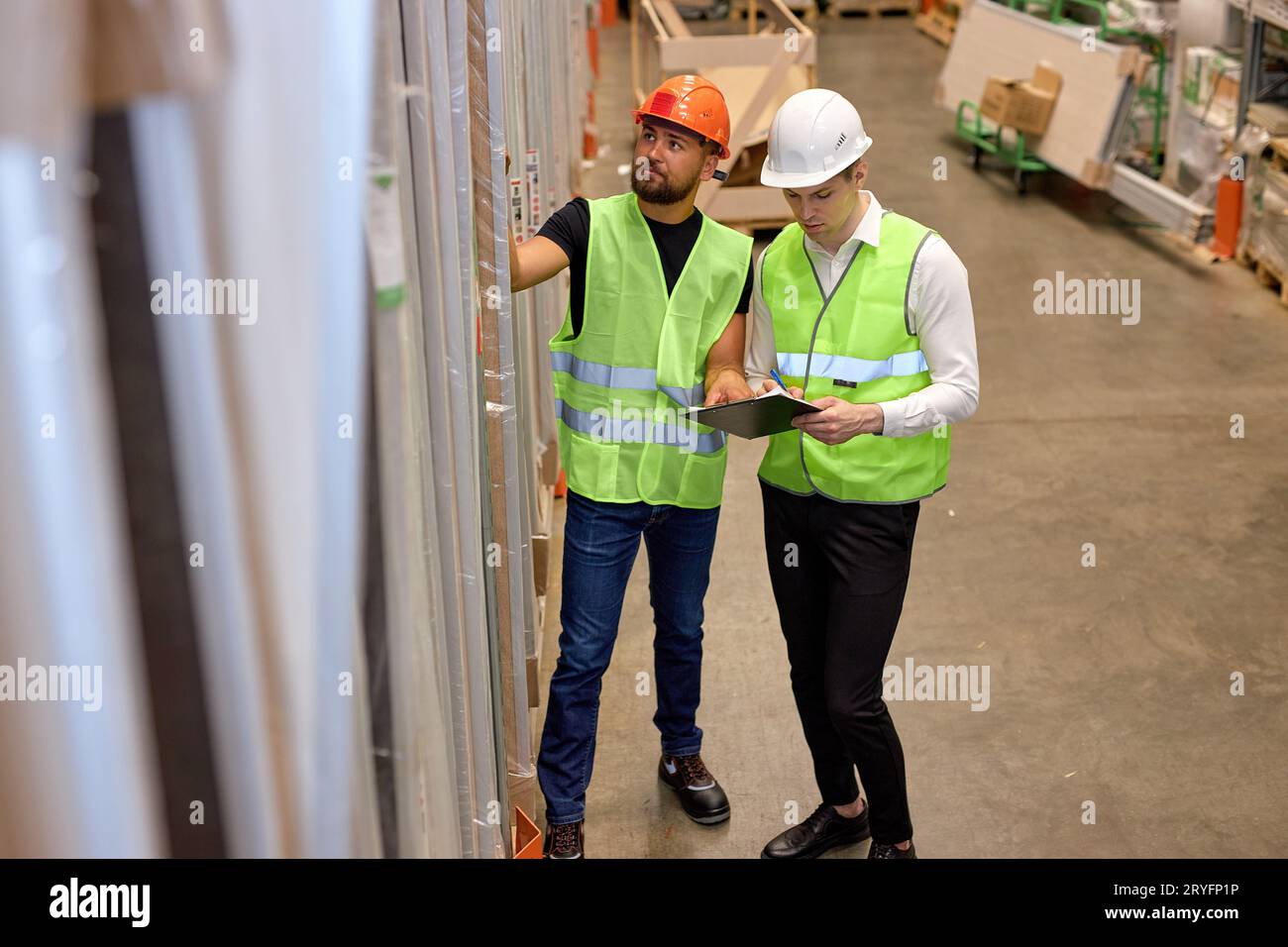 Focused men warehouse workers in working clothes uniforms talking ...