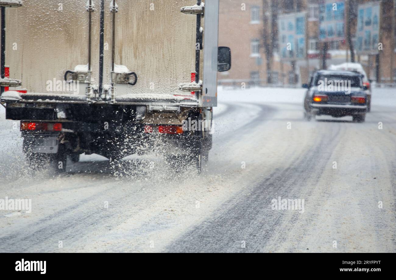 Road snow pieces flow from wheels of dirty truck moving fast in ...