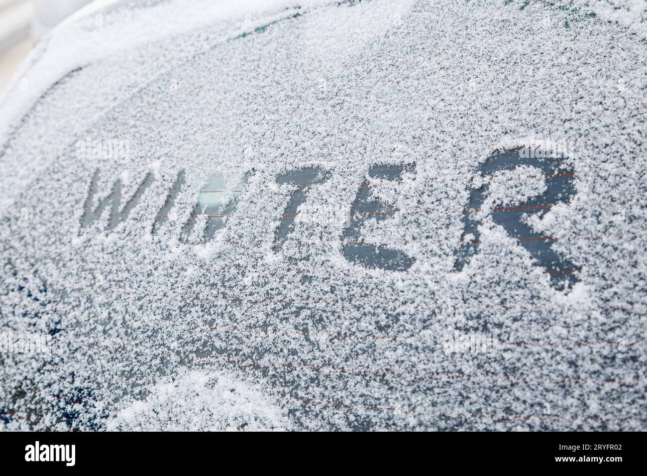 Word winter handwritten on snowy car window at winter morning light ...