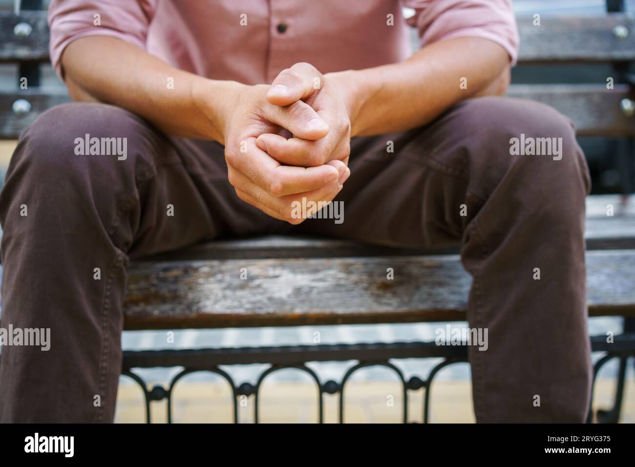 No face visible. Man spend time sitting on the bench with hands put ...