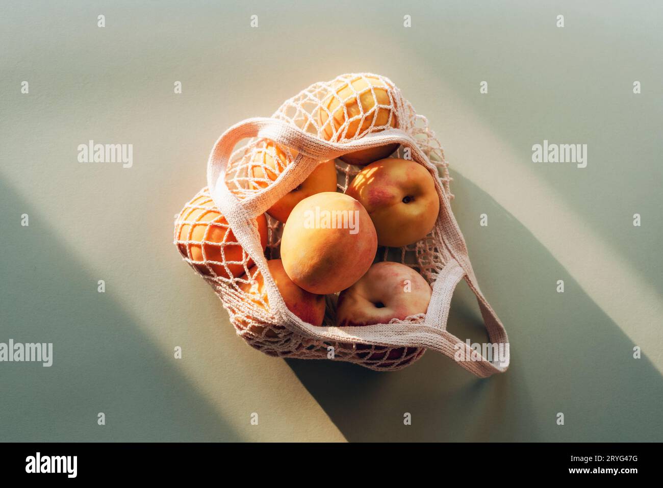 Fresh ripe peaches in a string bag in sunlight. Zero waste concept ...